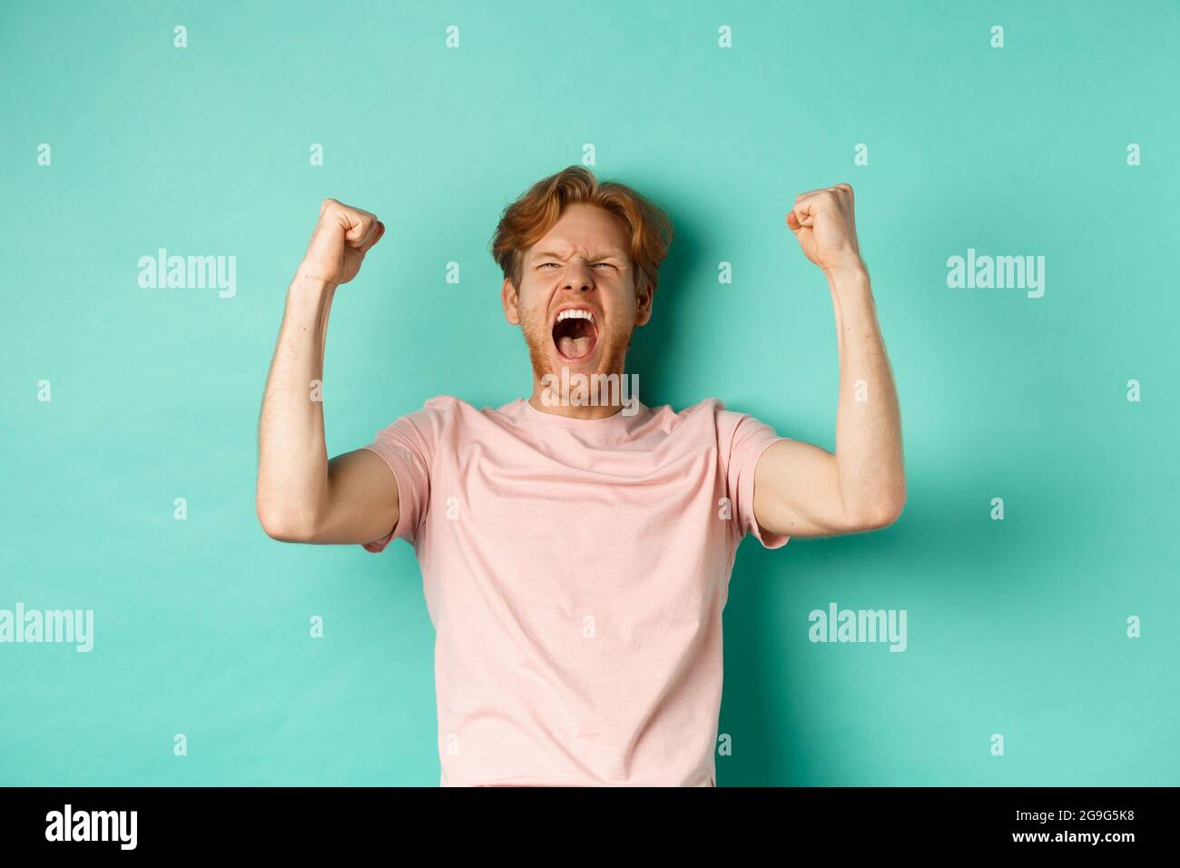 Young redhead man triumphing as watching sport game, making bet on ...