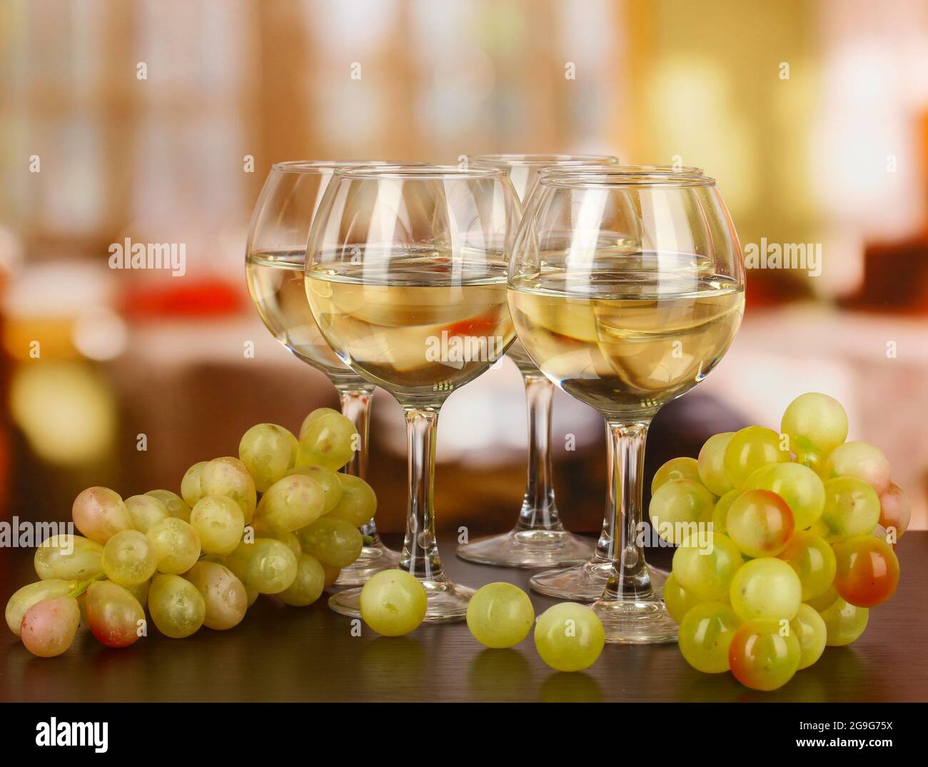White wine in glass on room background Stock Photo - Alamy