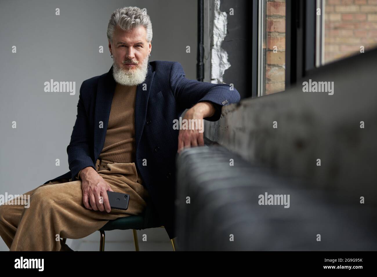 Stylish gray haired middle aged man in casual wear looking at camera ...