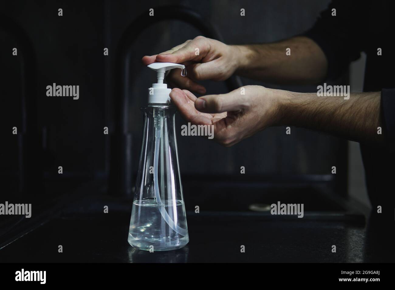 close up hands of male useing antiseptic in black background. palm ...