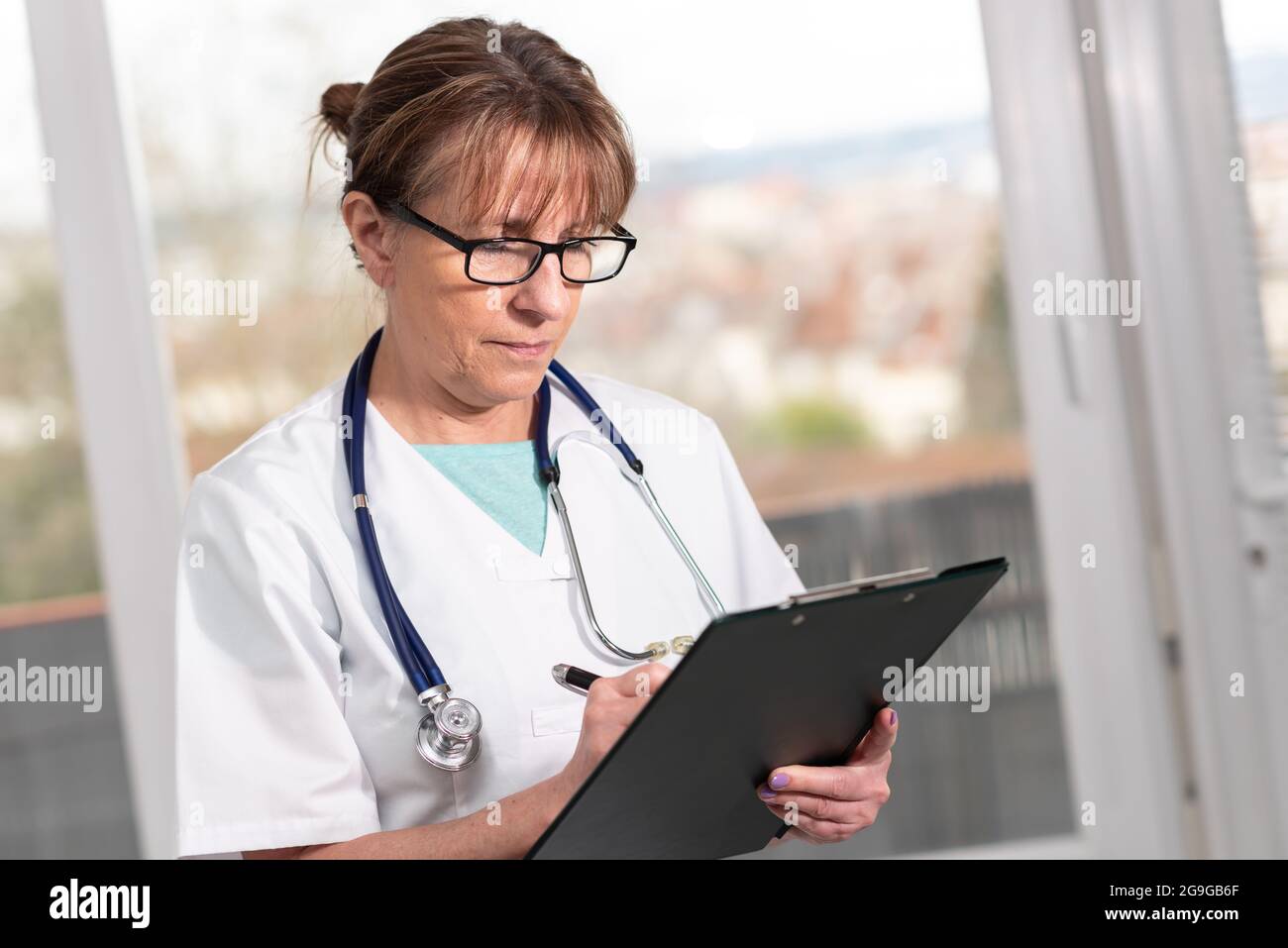 Female doctor standing and taking notes on clipboard hi-res stock ...