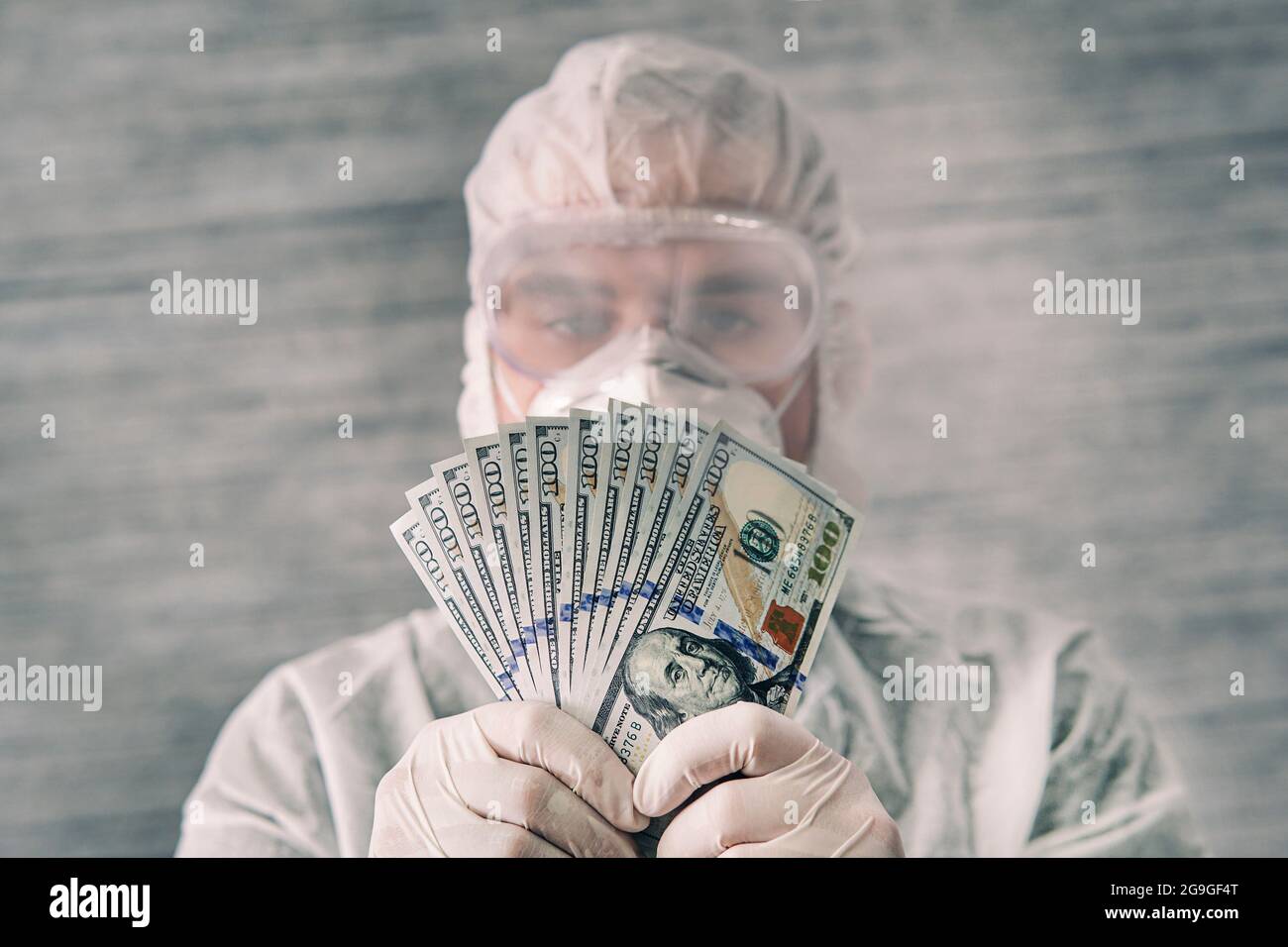 A doctor in a protective uniform holds cash bills in his hands. Payment ...