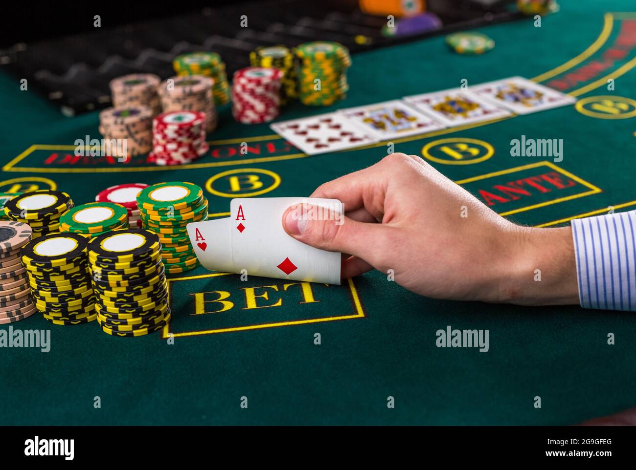 Male poker player lifting the corners of two cards aces Stock Photo - Alamy
