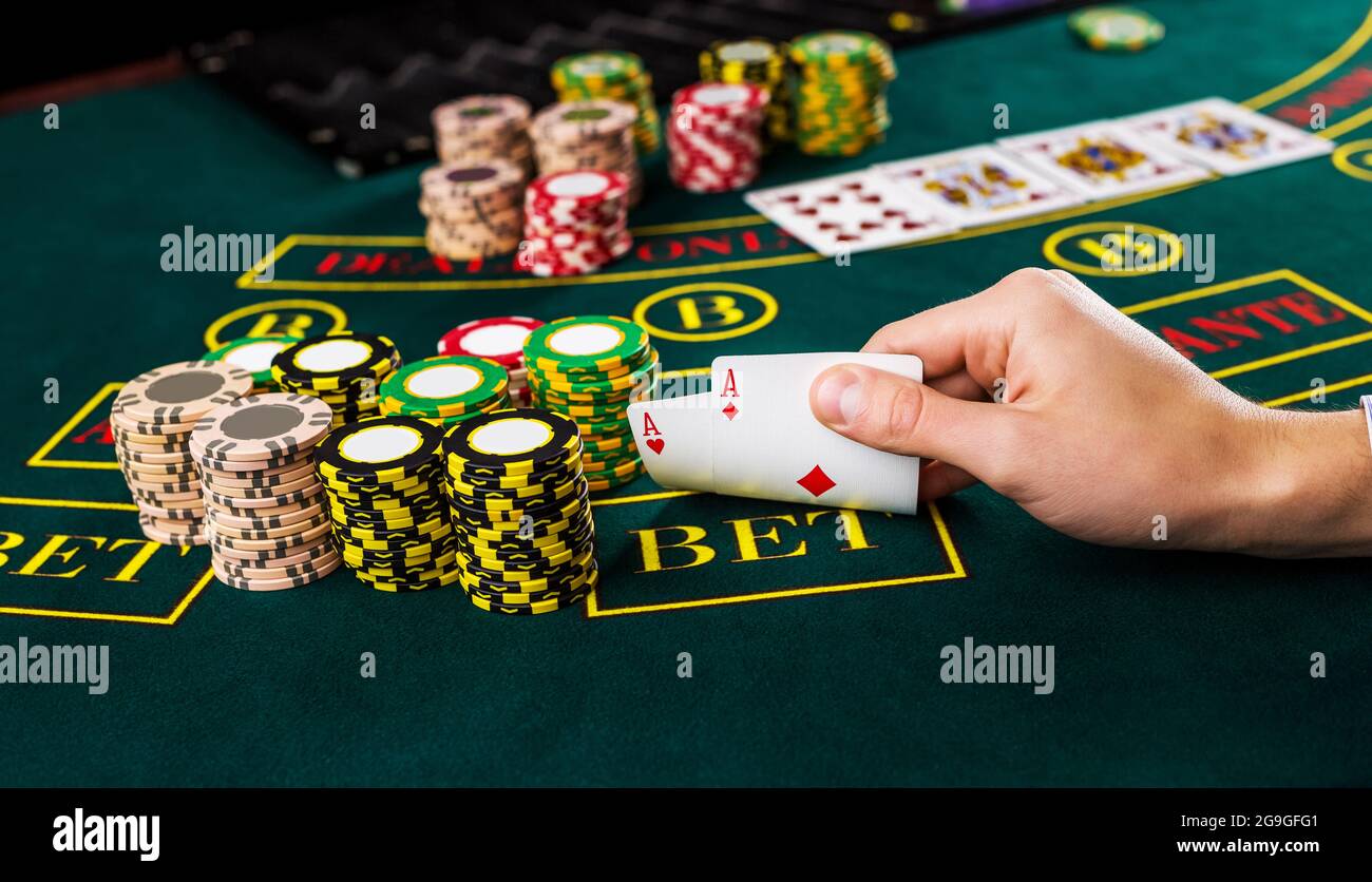 Male poker player lifting the corners of two cards aces Stock Photo - Alamy