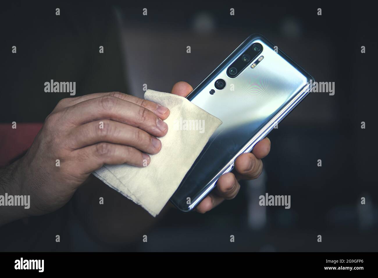 A man rubs the screen of his black smartphone with a rag. Prevention of ...