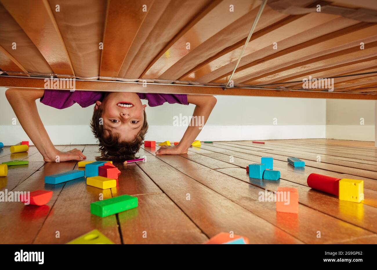 Boy look down under the bed stand on hands Stock Photo - Alamy