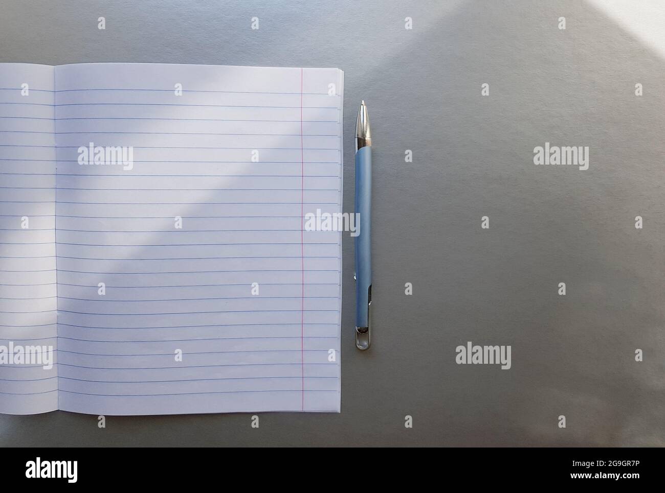 open school notebook with pen on a gray desk with sun rays from the ...