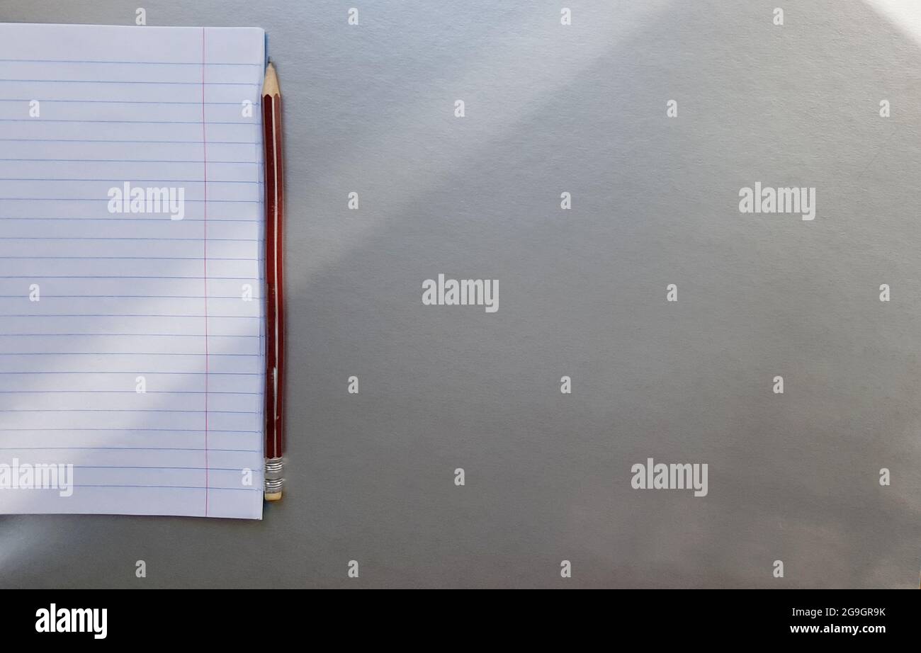 open school notebook with pen on a gray desk with sun rays from the ...