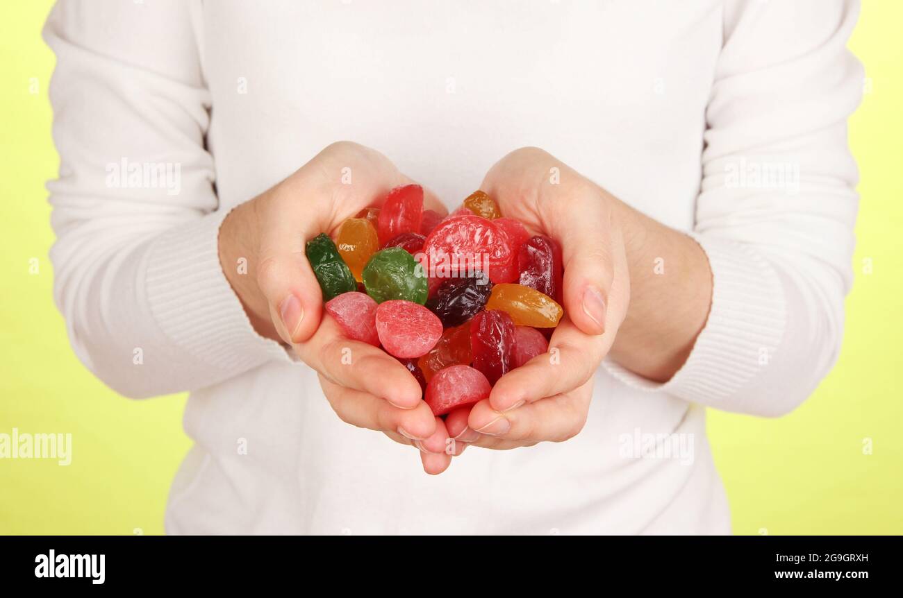 Hands full of sweets on green background Stock Photo - Alamy
