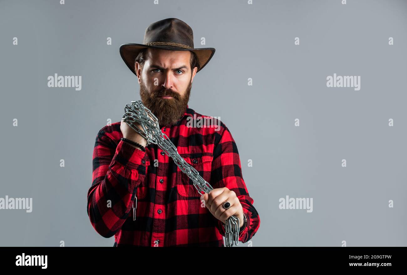 brutal cowboy man with beard and mustache pull steel chain, trap ...