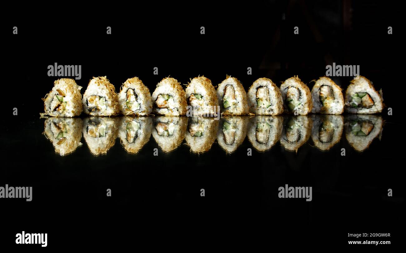 triangular japanese sushi in a row on a black background with ...