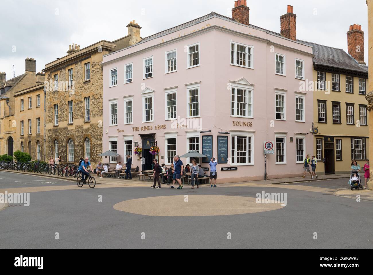 Passers by and people enjoying refreshments seated at tables outside ...