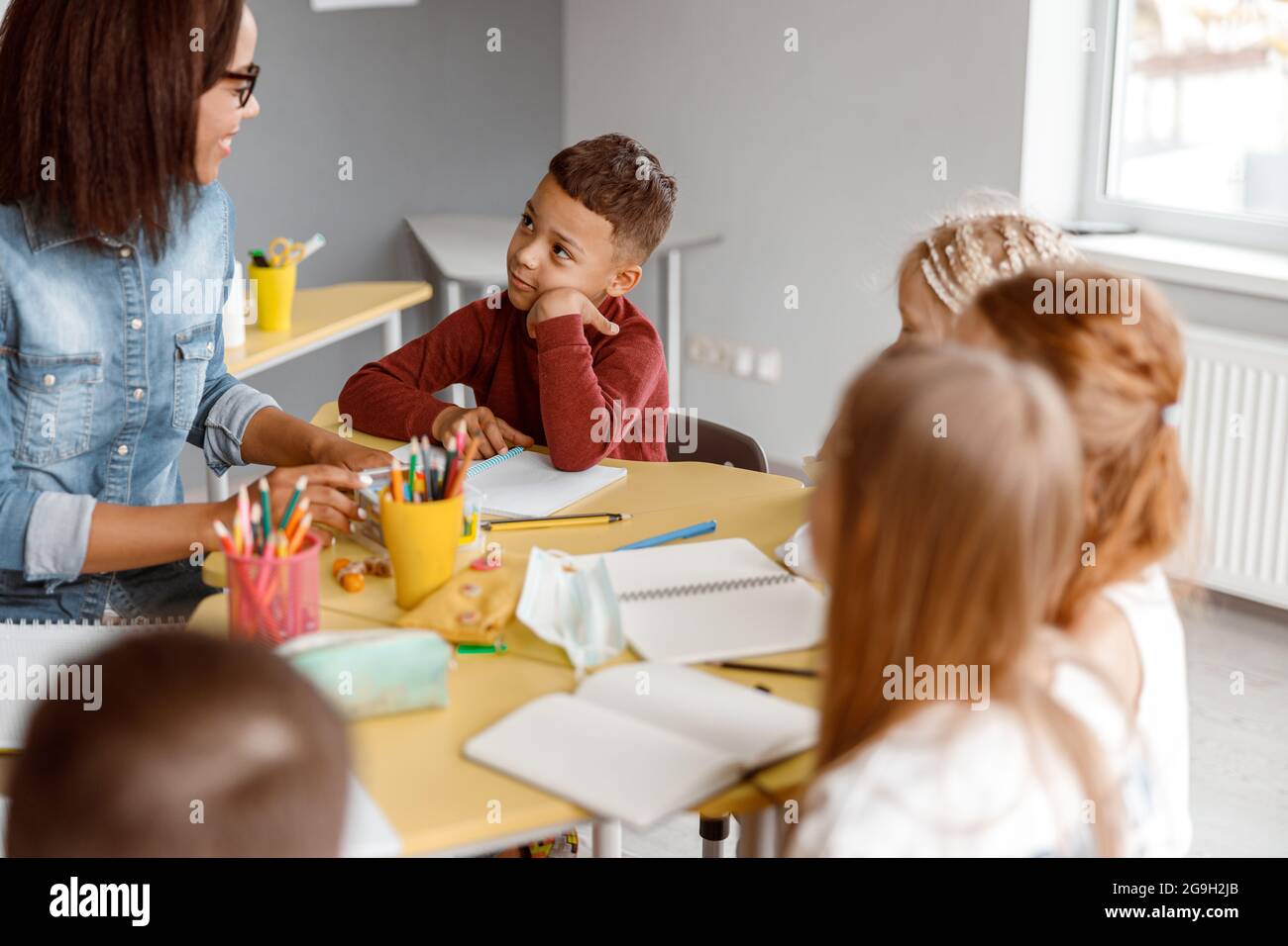 Smiling teacher having a lesson with kids in the classroom Stock Photo ...