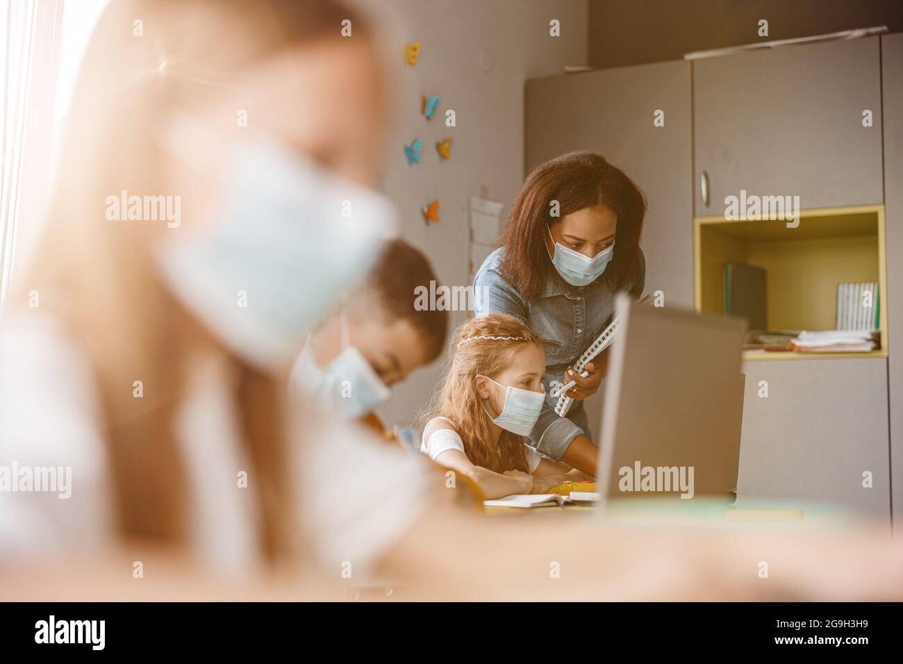 Young teacher and girl looking at laptop screen in class Stock Photo ...