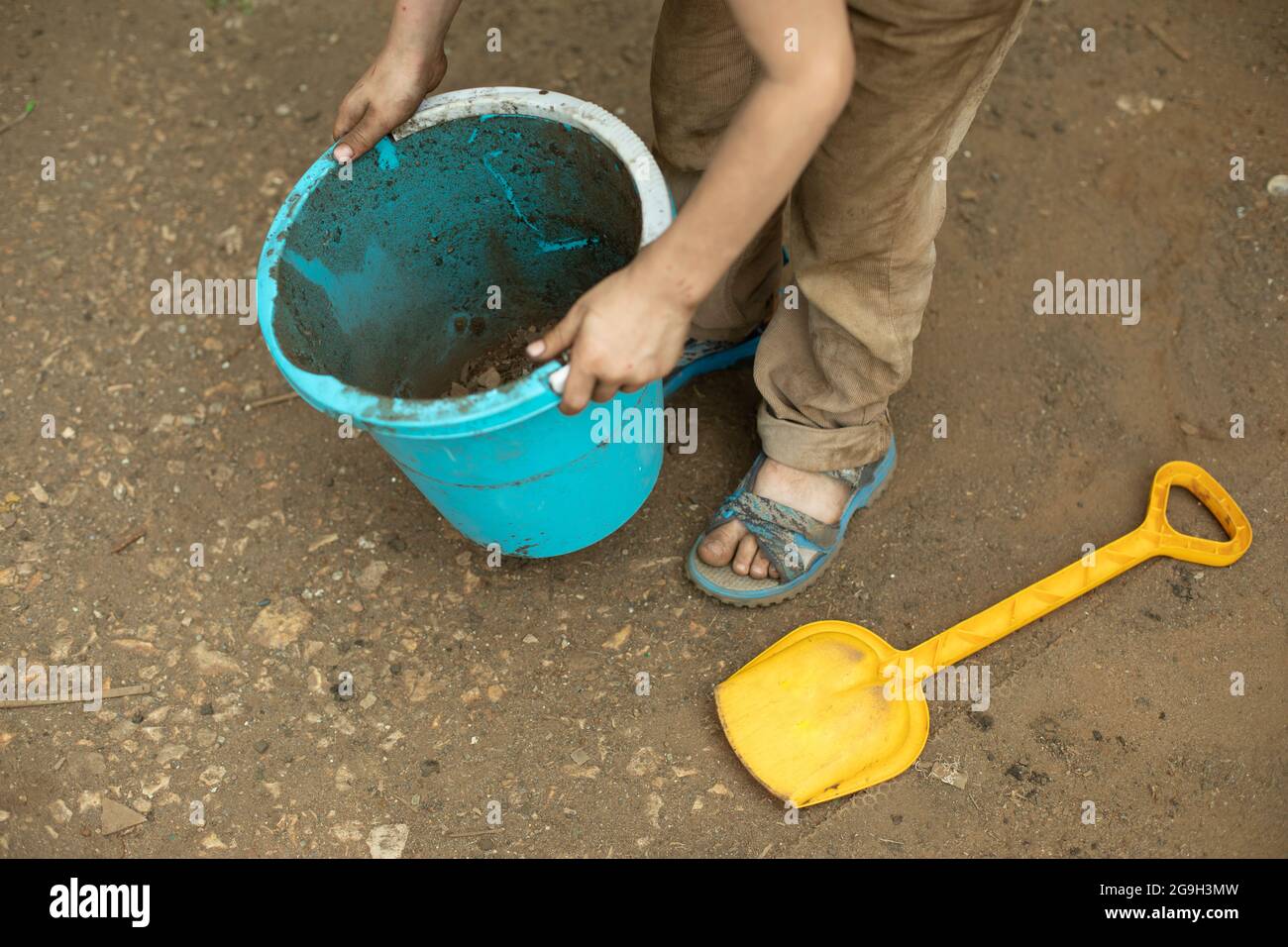 The child is holding a bucket. Blue bucket in hand. The boy plays with ...