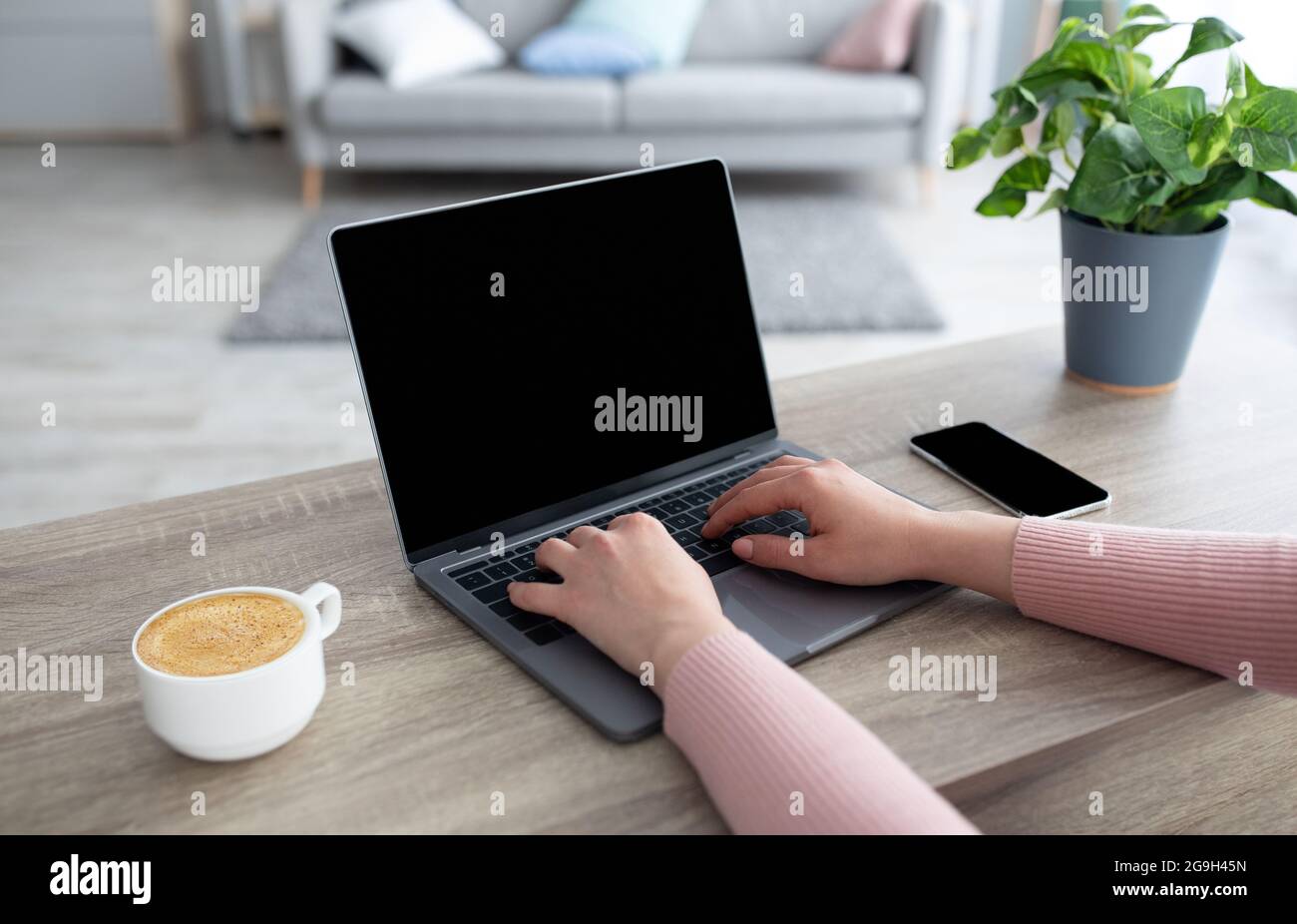 Unrecognizable woman working on laptop computer with blank black screen ...