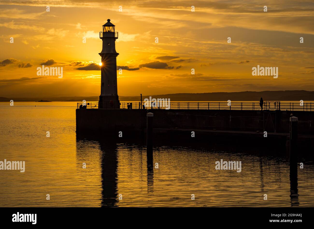 Newhaven harbour lighthouse silhouetted in a colourful orange sky with ...