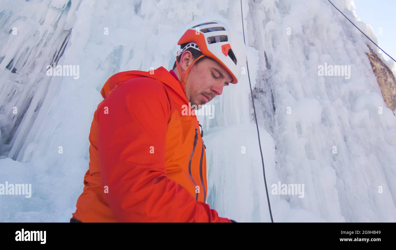 Ice climber, with gloved hands, tying a rope to his harness Stock Photo ...