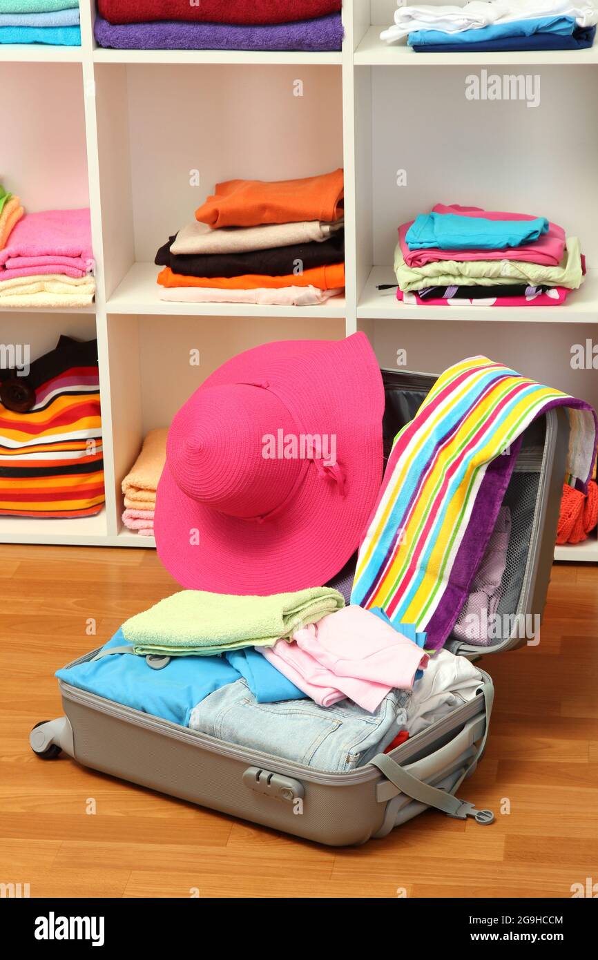 Open silver suitcase with clothing in room Stock Photo - Alamy