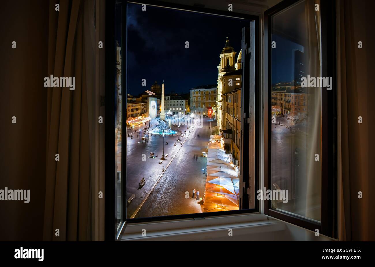 View through an open window of the Piazza Navona at night with the ...