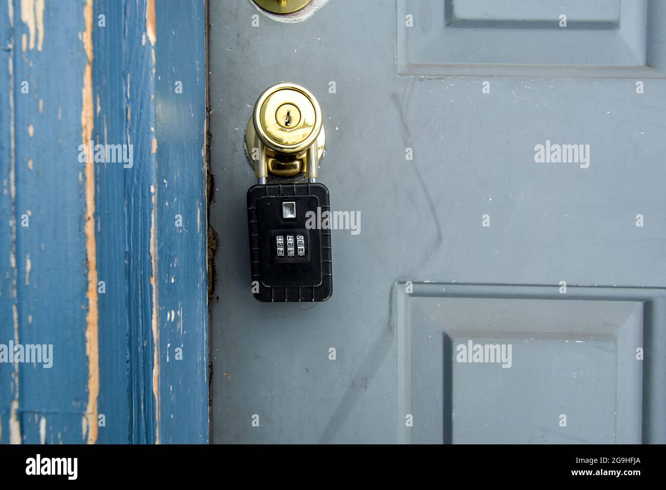 A closed combination lockbox padlock with letters on a worn door knob ...