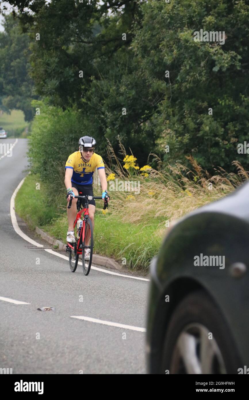 cyclist on a road in the surrey hills with front of car coming in ...