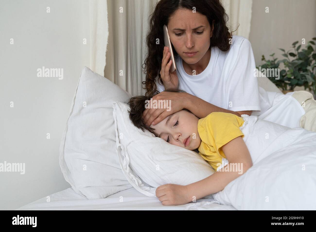 Worried mother call to doctor checking temperature of sick kid lying in ...