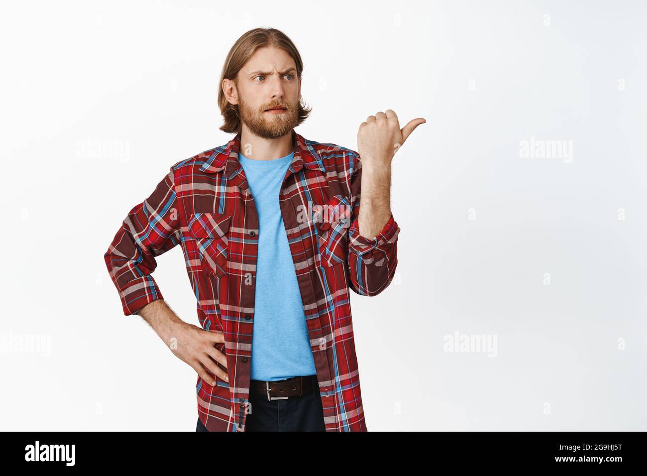 Confused blond man pointing right with frowned face, see smth strange ...
