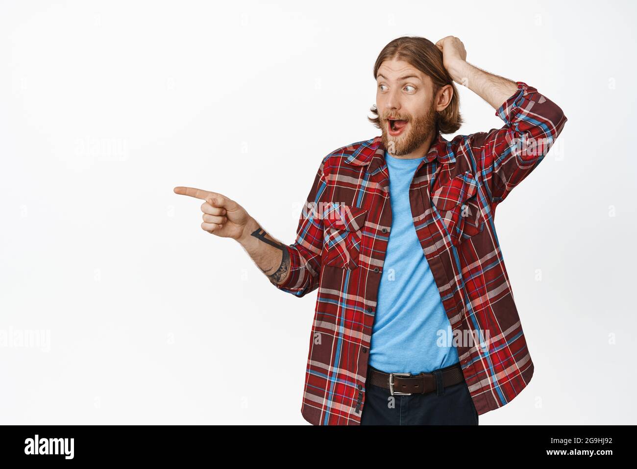Portrait of surprised blond man pointing finger left and looking at ...