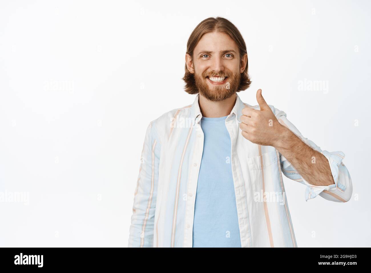 Portrait of handsome blond man smiling, showing thumb up with confident ...