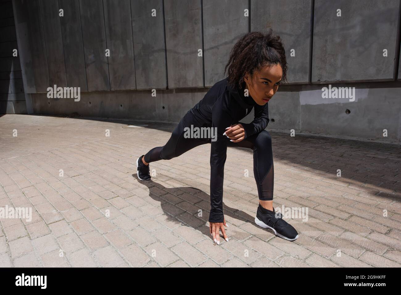 African american runner standing in starting pose on urban street Stock ...