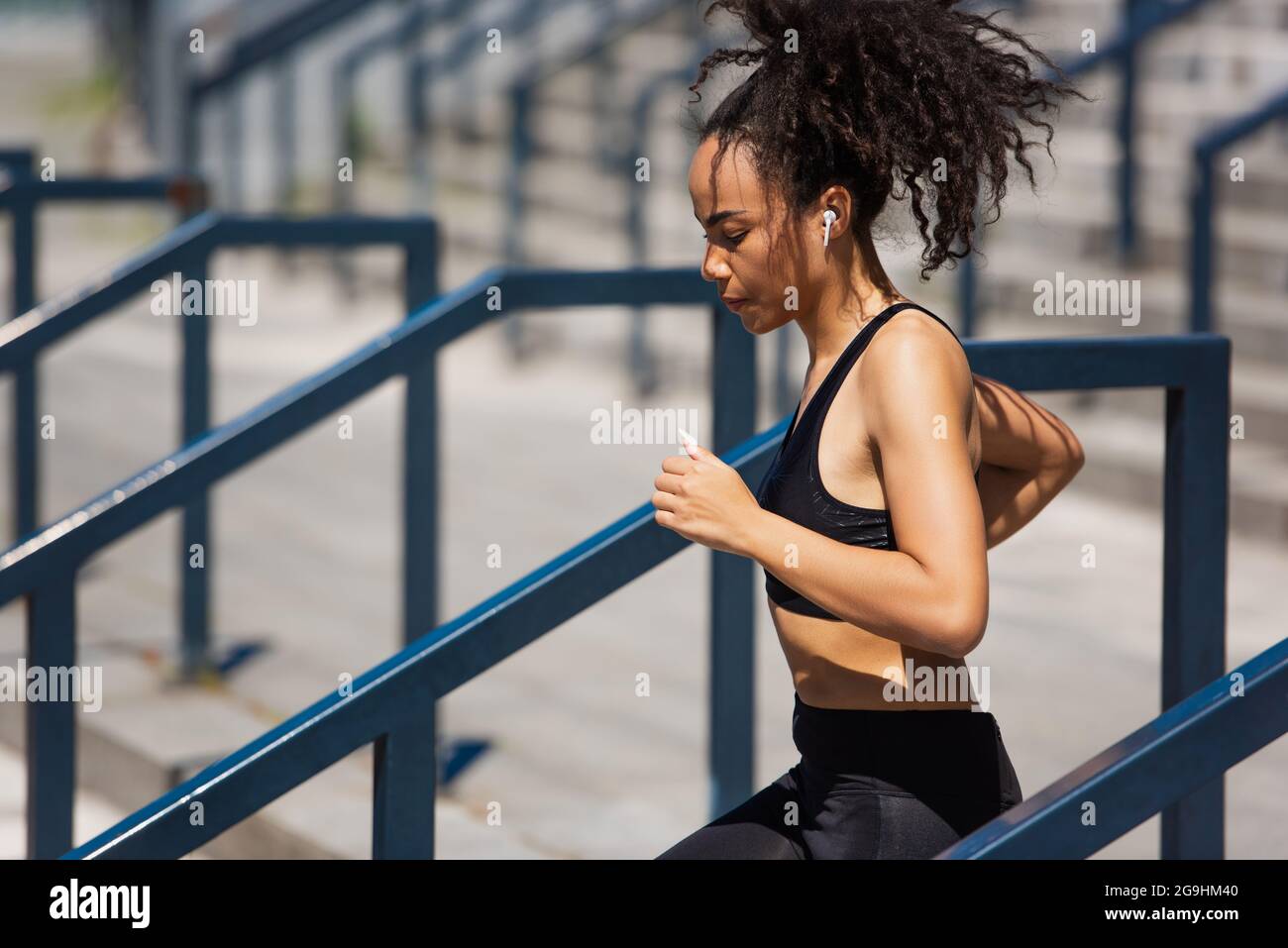 Side view of african american woman using earphone while running ...