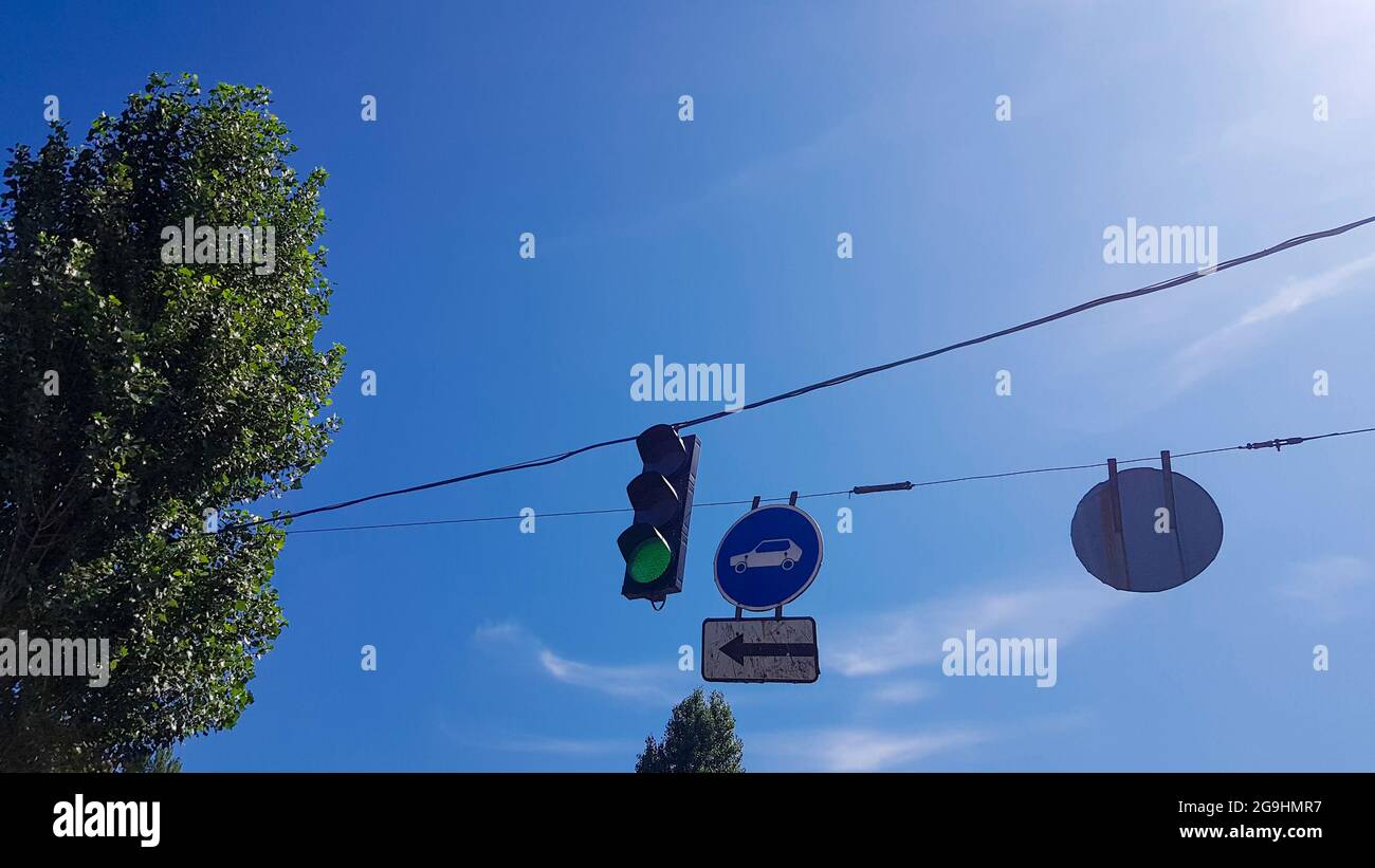 Traffic light and signs on the street close up with a burning green ...