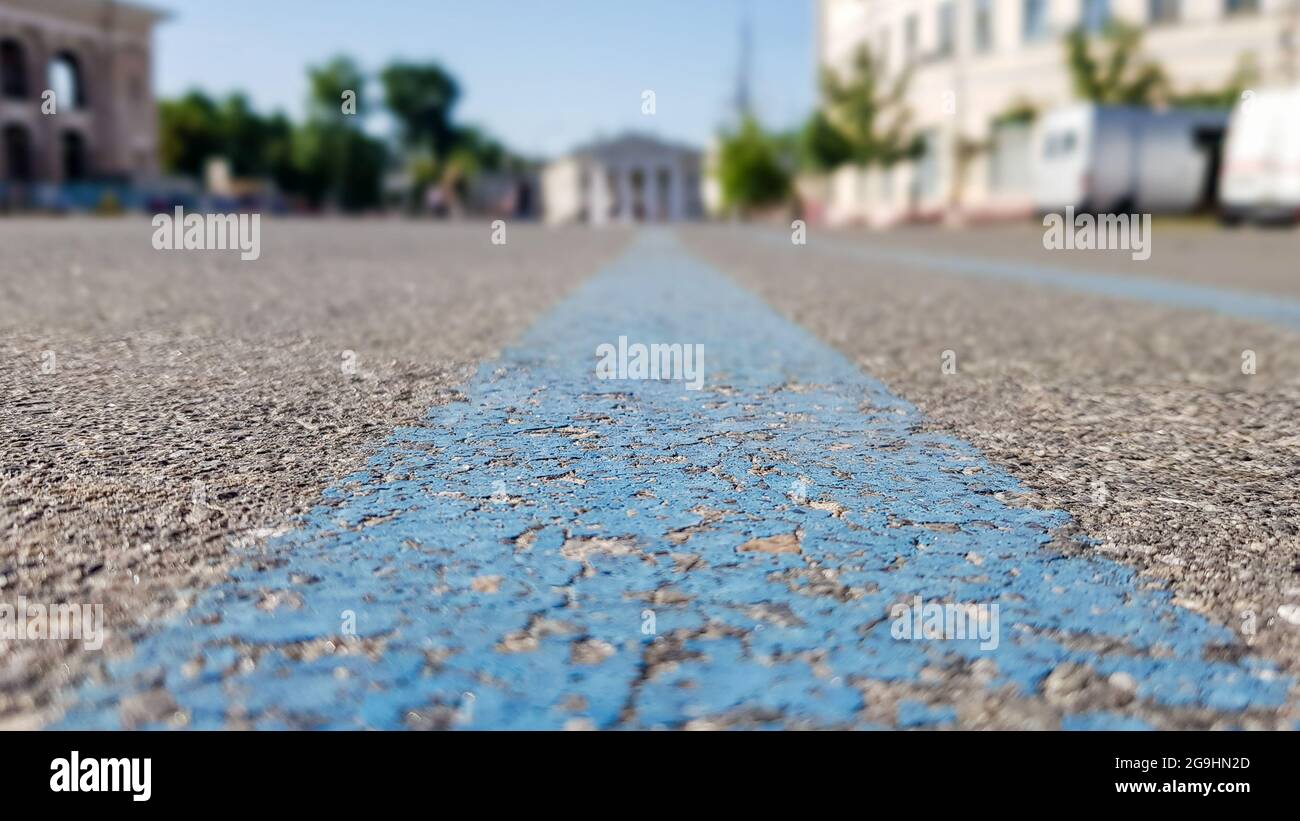 A wide blue stripe on an asphalt-black surface. asphalt road in the ...