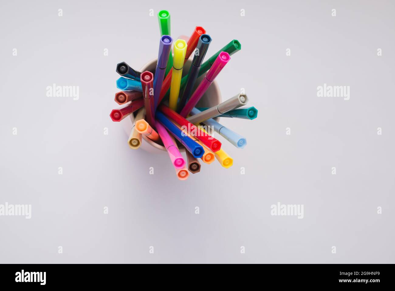 Cup full of markers seen from above. White background and copy space ...