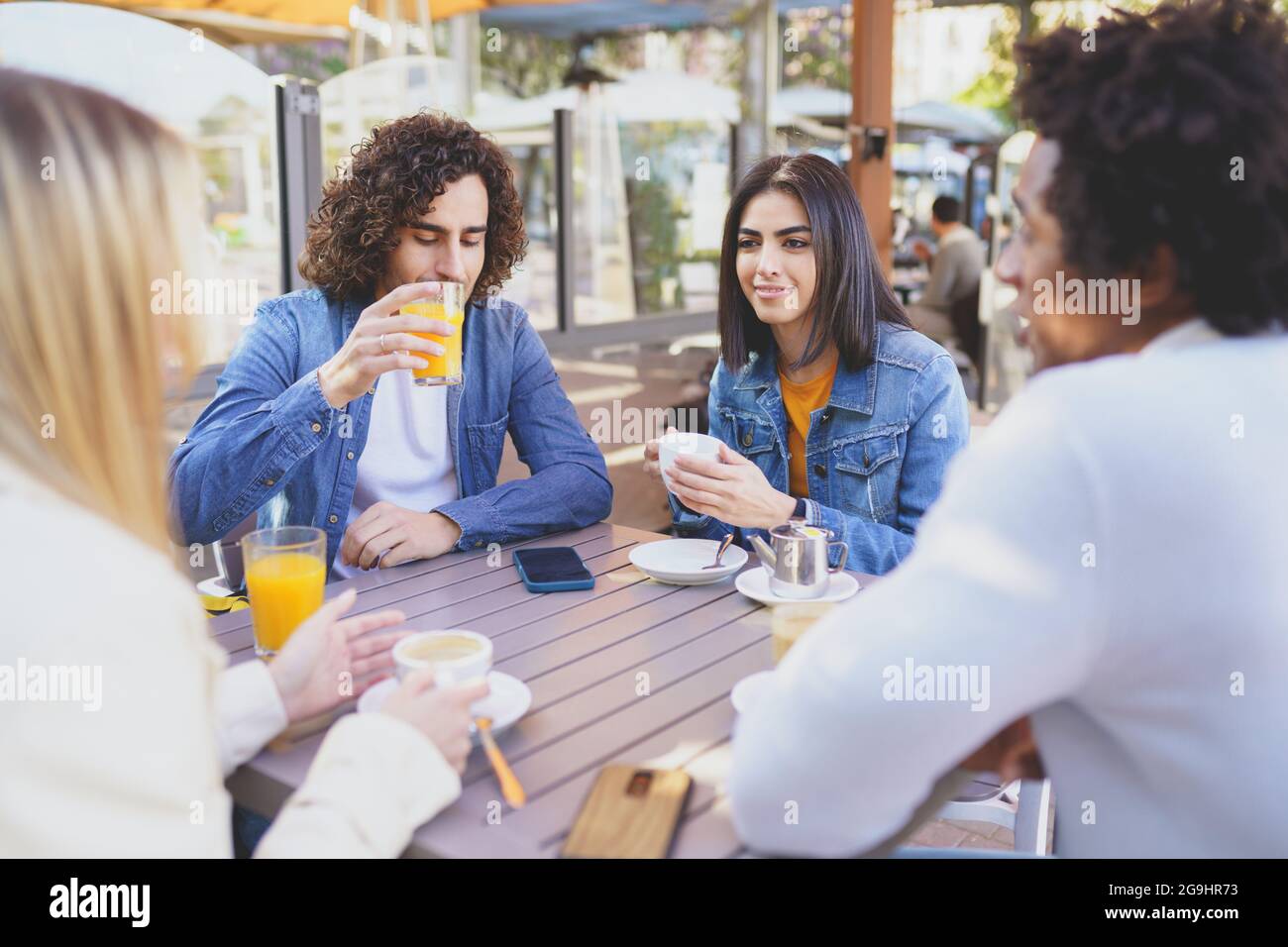 Multi-ethnic group of friends having a drink together in an outdoor bar ...