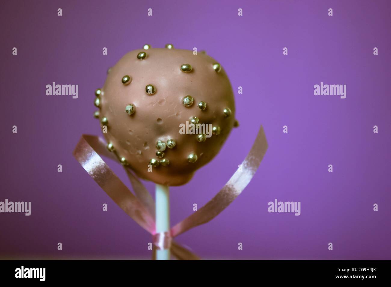 Pink chocolate cake pops with strawberry flavour on a purple background ...