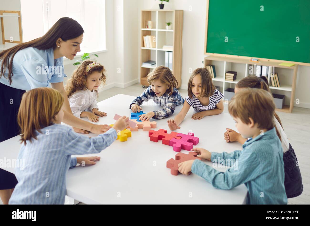 Group of creative students with teacher putting together pieces of ...