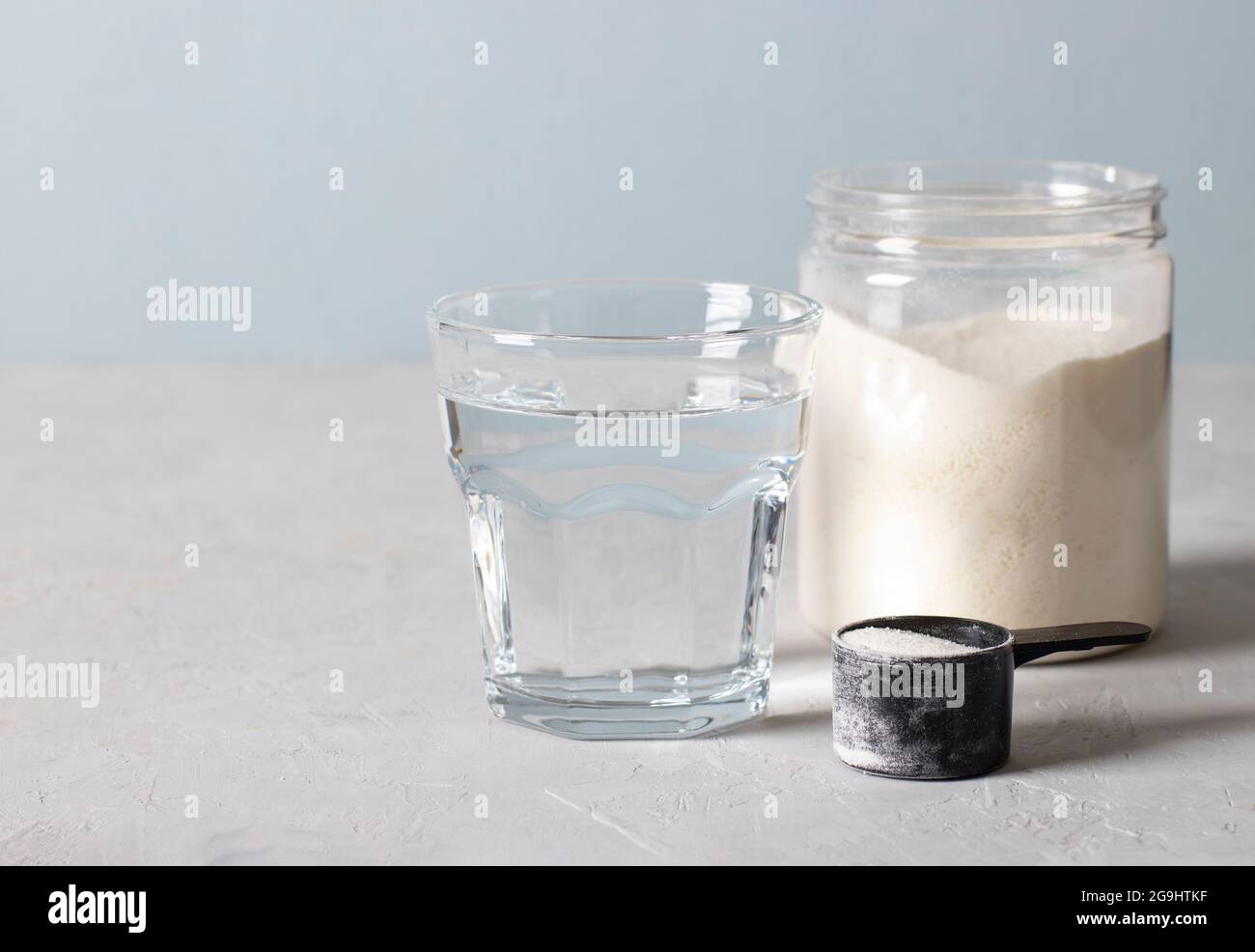 Glass of water, collagen powder in a jar and a measuring spoon with ...