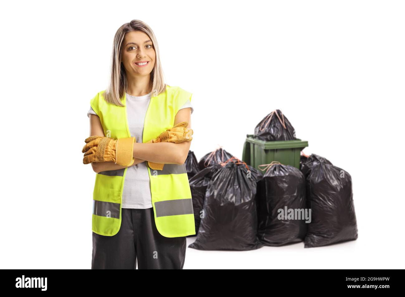 Woman waste collector in a uniform posing in front of a pile of bags ...