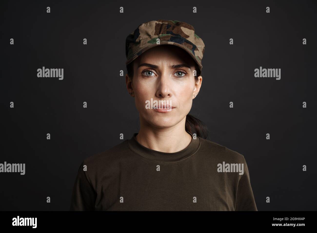 Serious beautiful soldier woman posing and looking at camera isolated ...