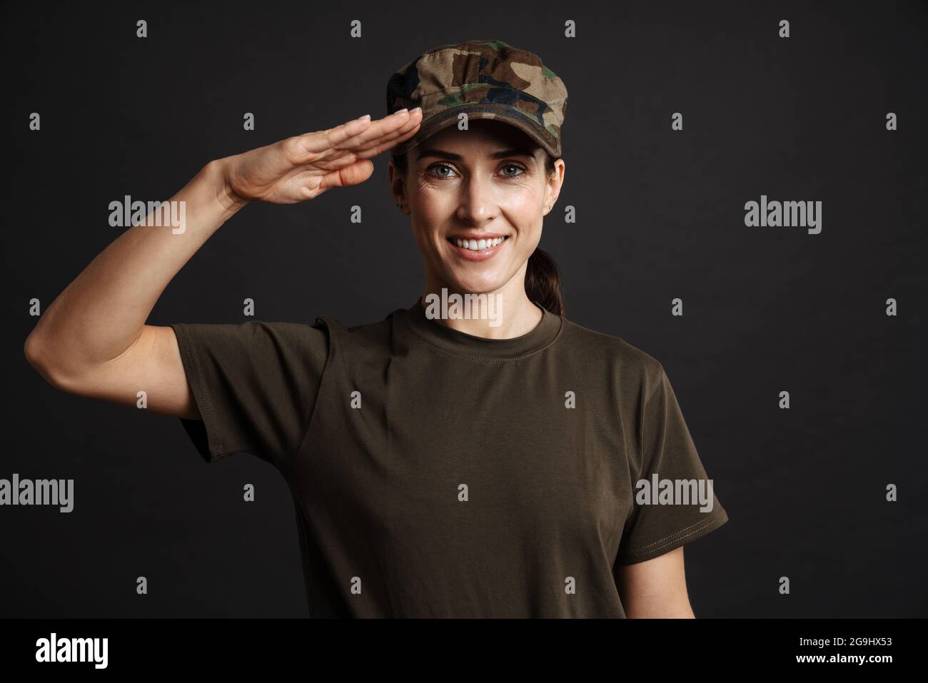 Happy beautiful soldier woman saluting and smiling at camera isolated ...