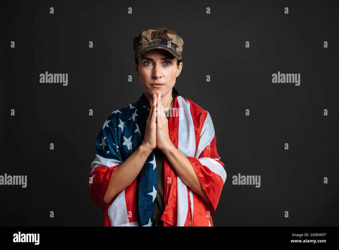 Calm soldier woman with american flag holding palms together isolated ...