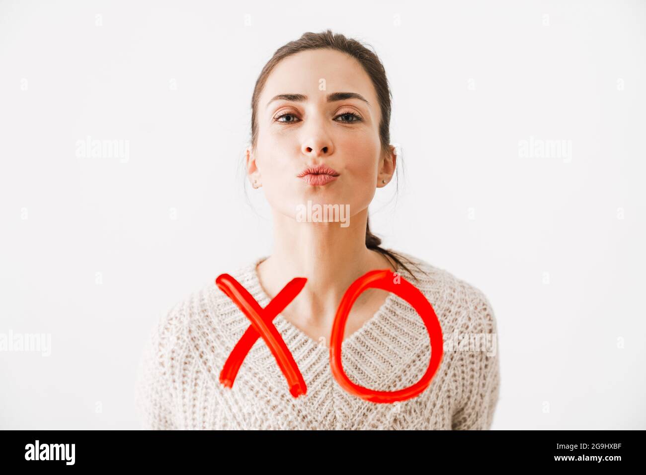 Lovely young woman in love kissing camera with xo symbol in front of ...