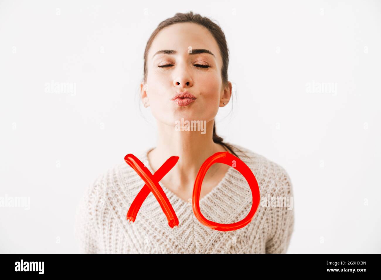 Lovely young woman in love kissing camera with xo symbol in front of ...