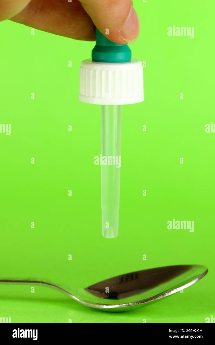 Medical droplet in spoon on green background Stock Photo - Alamy