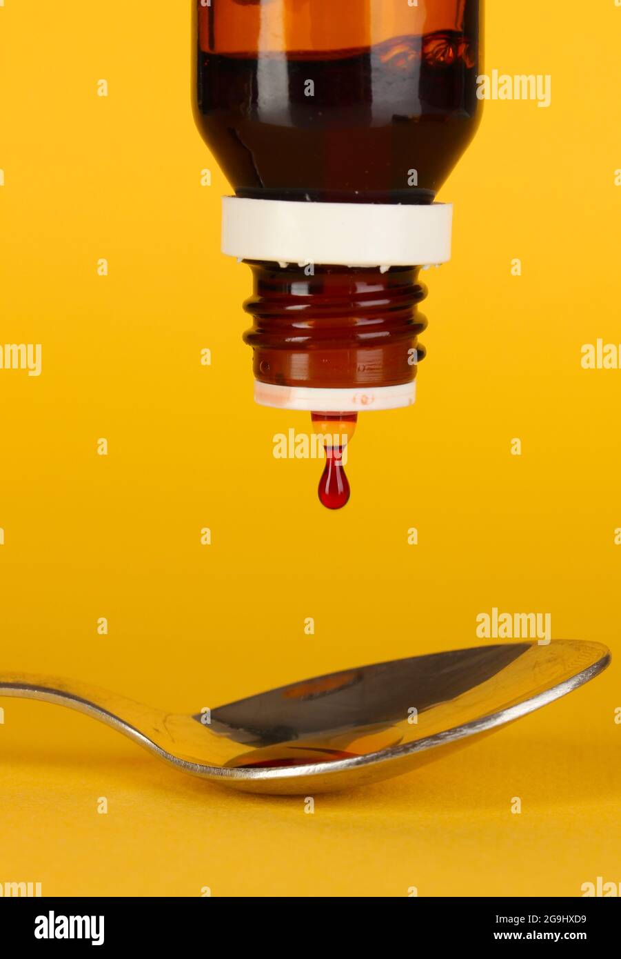 Medical droplet in spoon on yellow background Stock Photo - Alamy