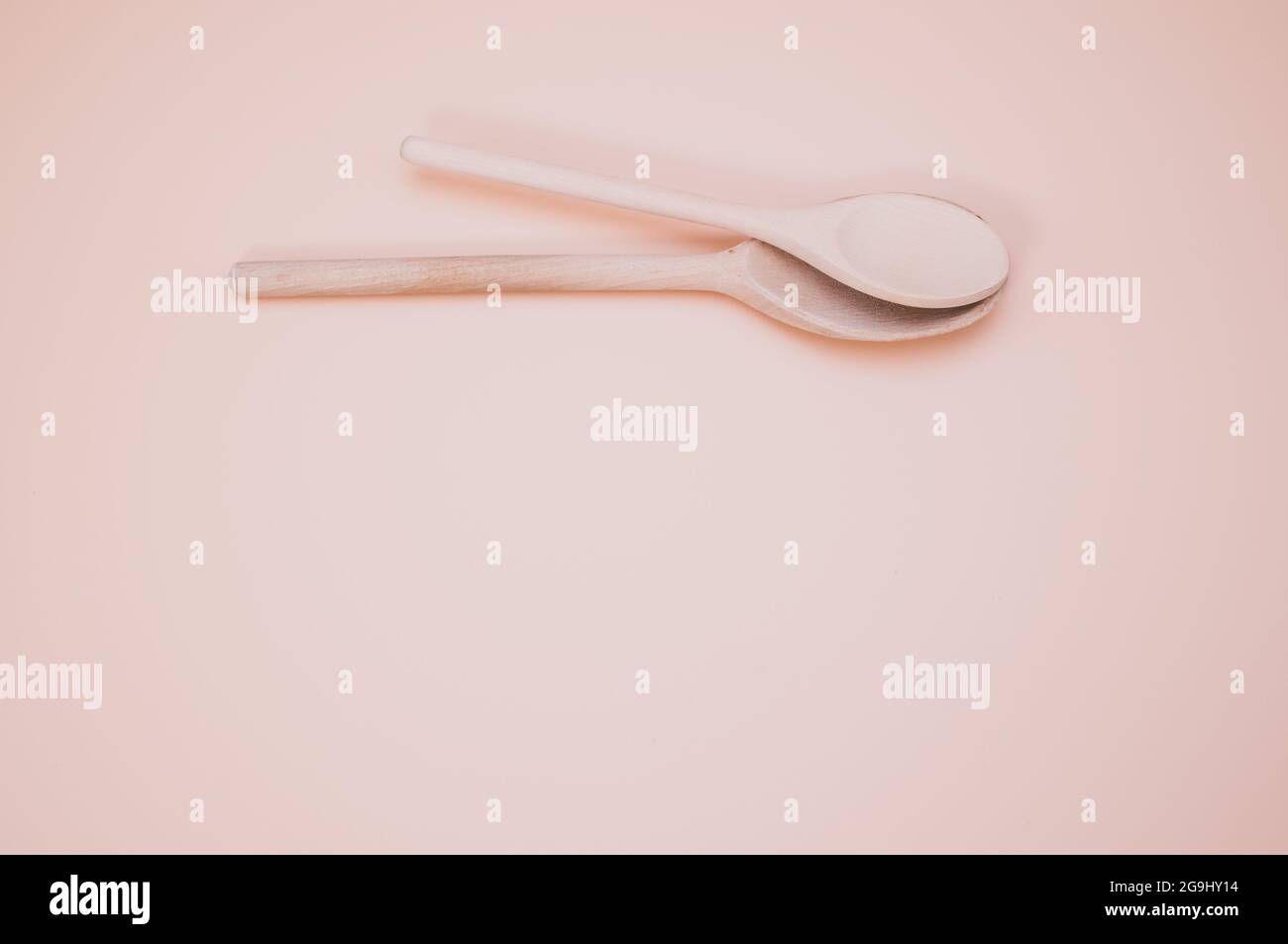 closeup of wooden spoons on an aesthetic peach background with copy ...