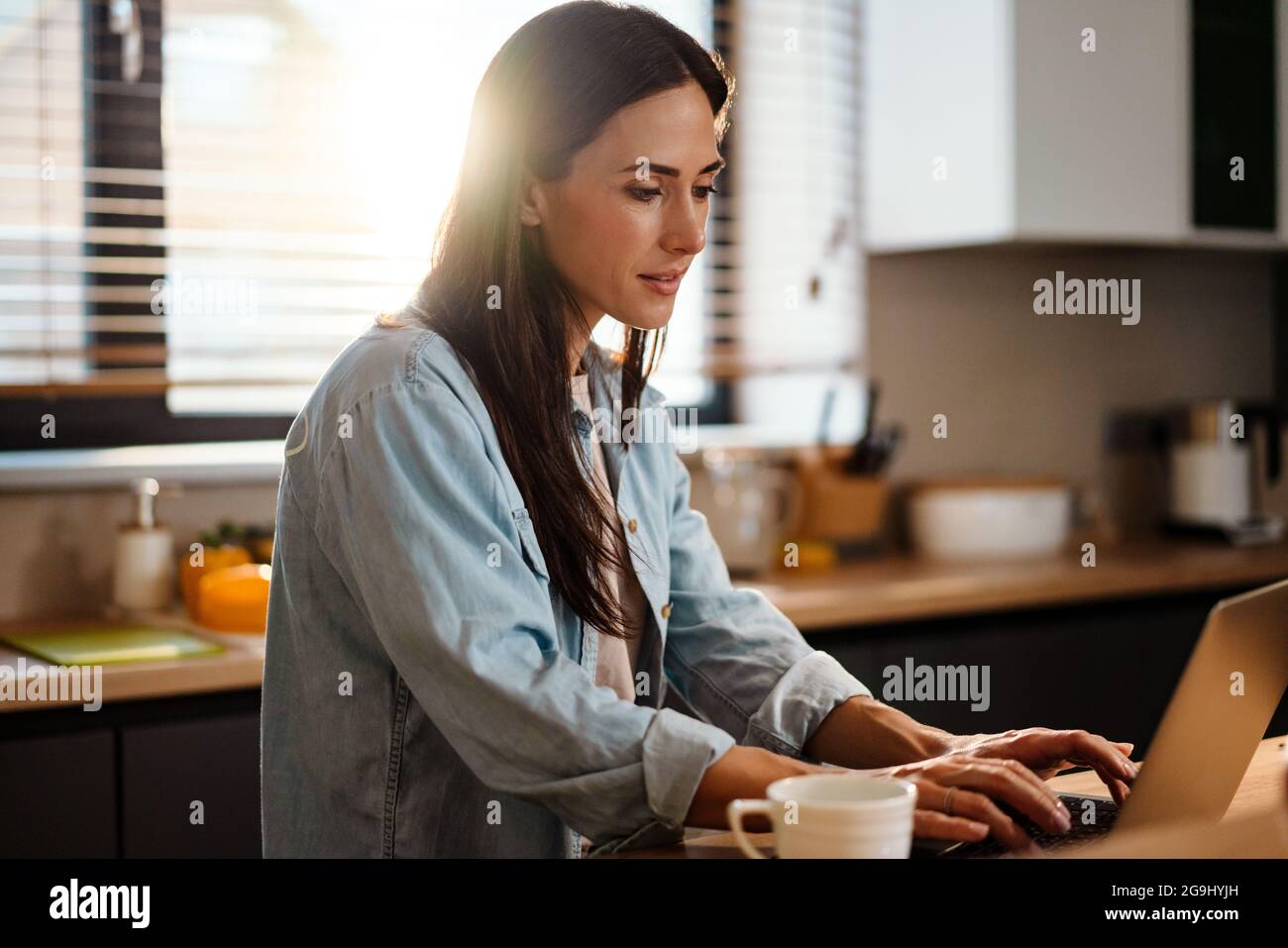 Attractive smiling young smart woman working on laptop computer while ...