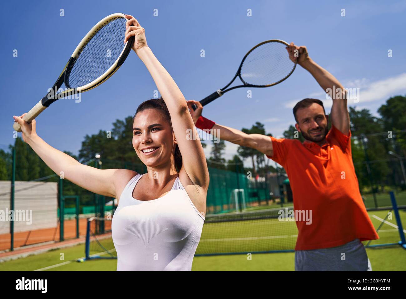 Two tennis players stretching their arm muscles using their rackets ...
